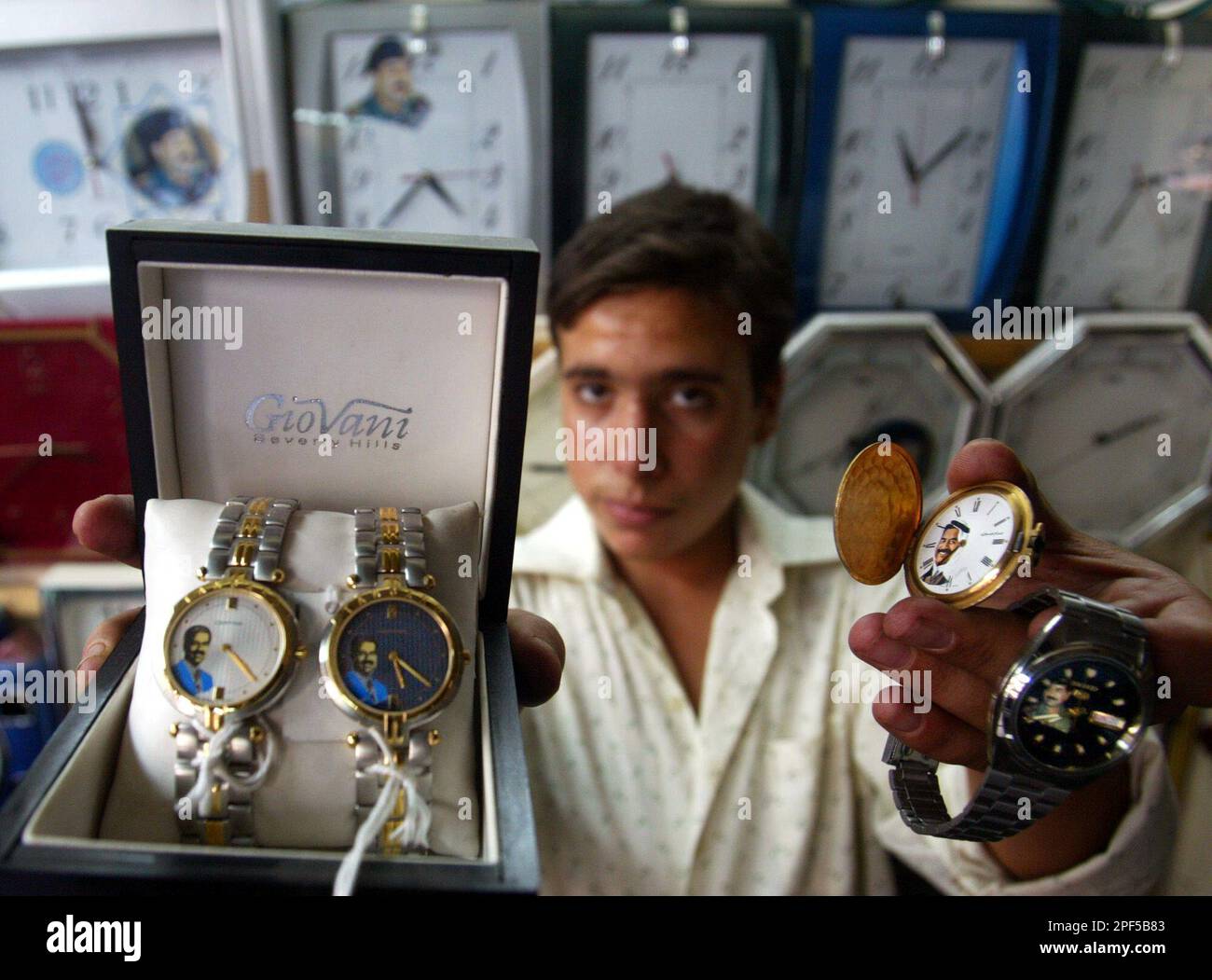 A young Iraqi shopkeeper shows wrist watches with Saddam Hussein ...