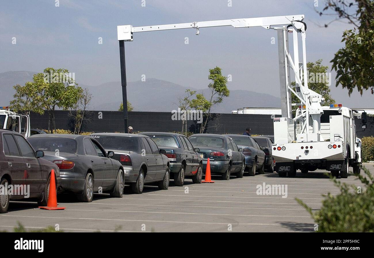 A truck with a giant x-ray arm passes over a line of vehicles at the ...