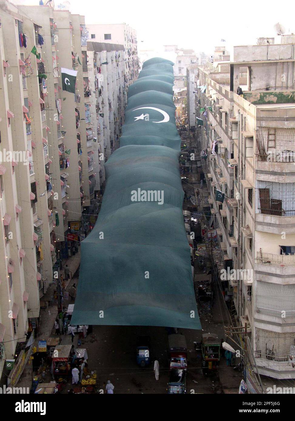 A huge Pakistani flag is hoisted between buildings in a congested ...