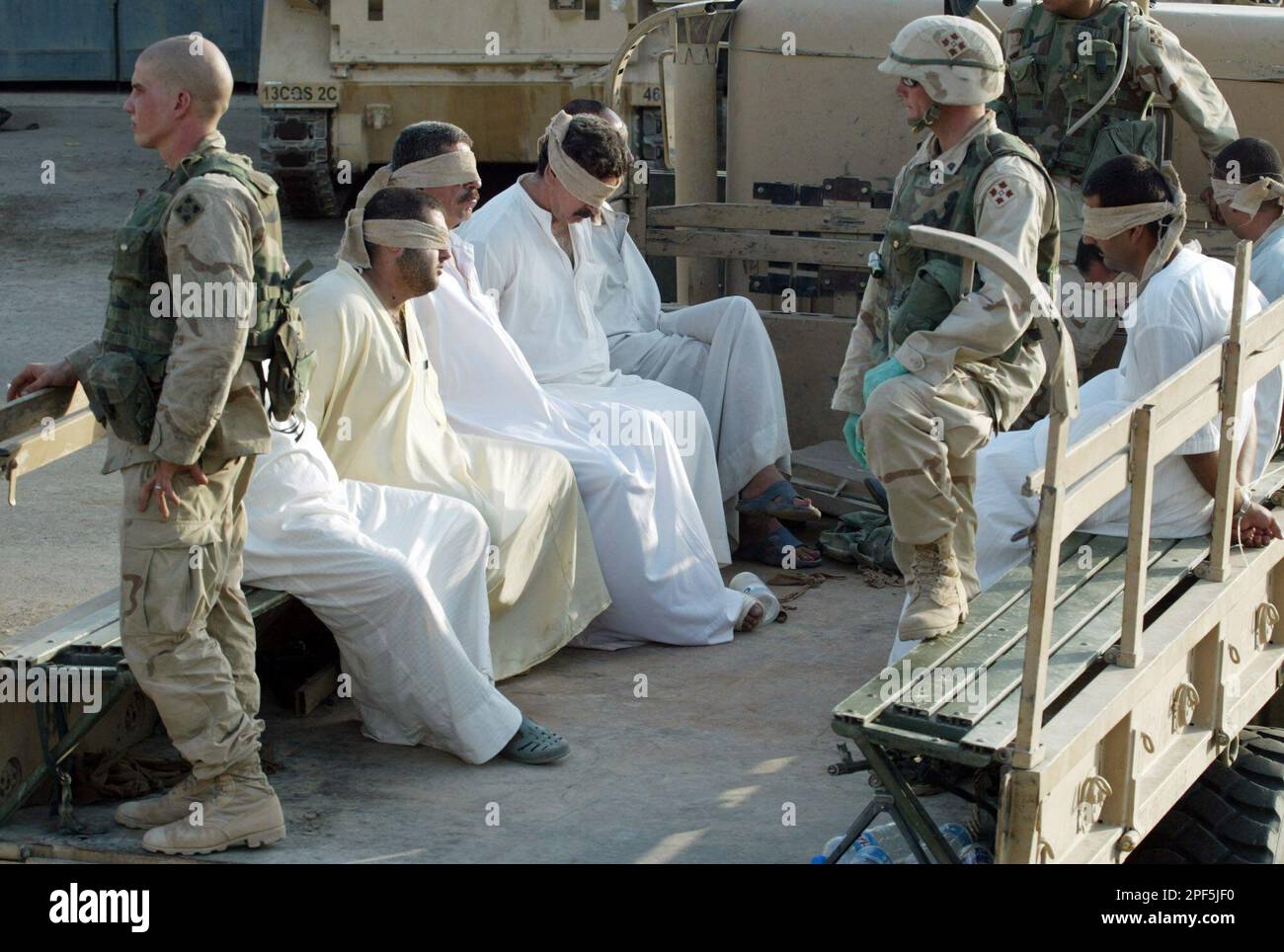 Blindfolded Iraqi detainees sit in a military truck in a U.S. army base ...