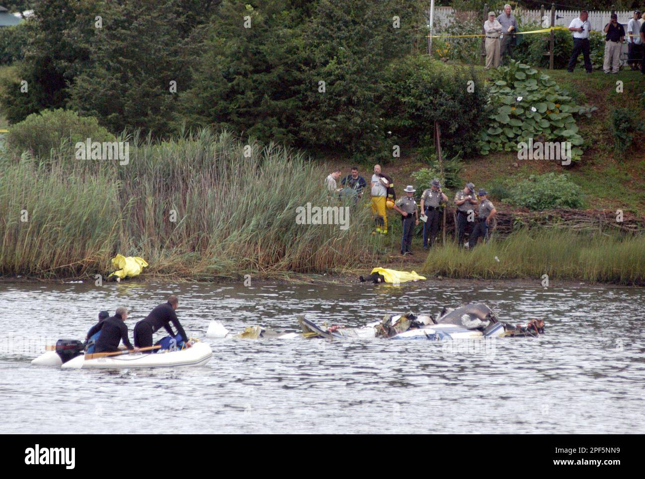 Police in a small boat check the wreckage of a Learjet that crashed ...