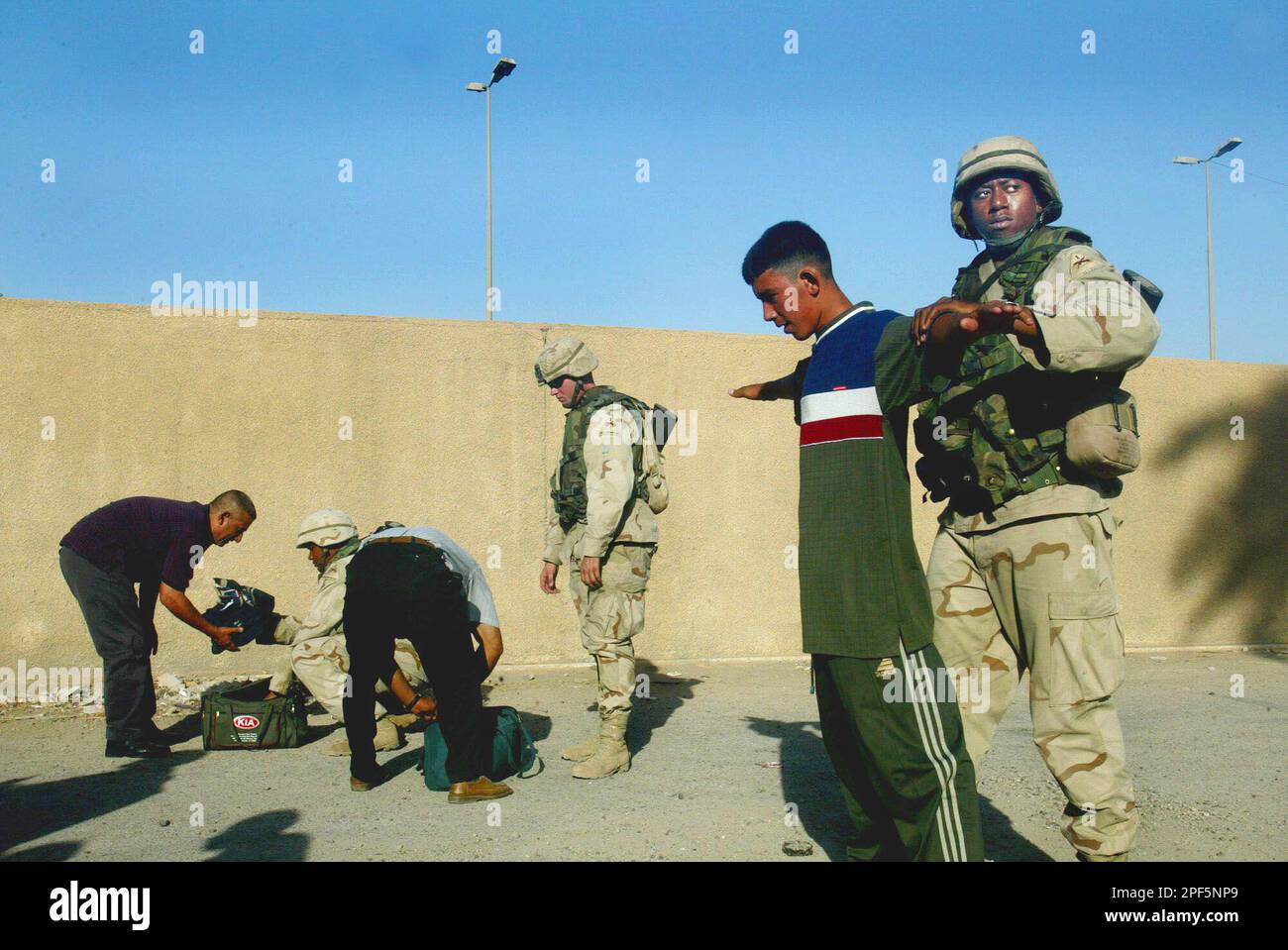U.S. soldiers frisk newly recruited Iraqi soldiers, before they leave ...