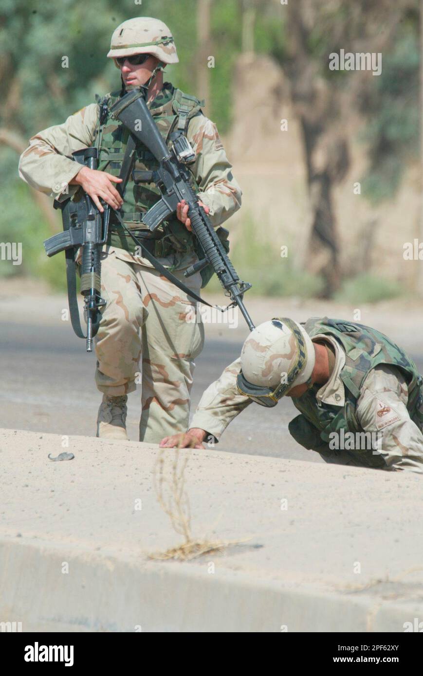 US soldiers look for improvised explosive device by a roadside in ...