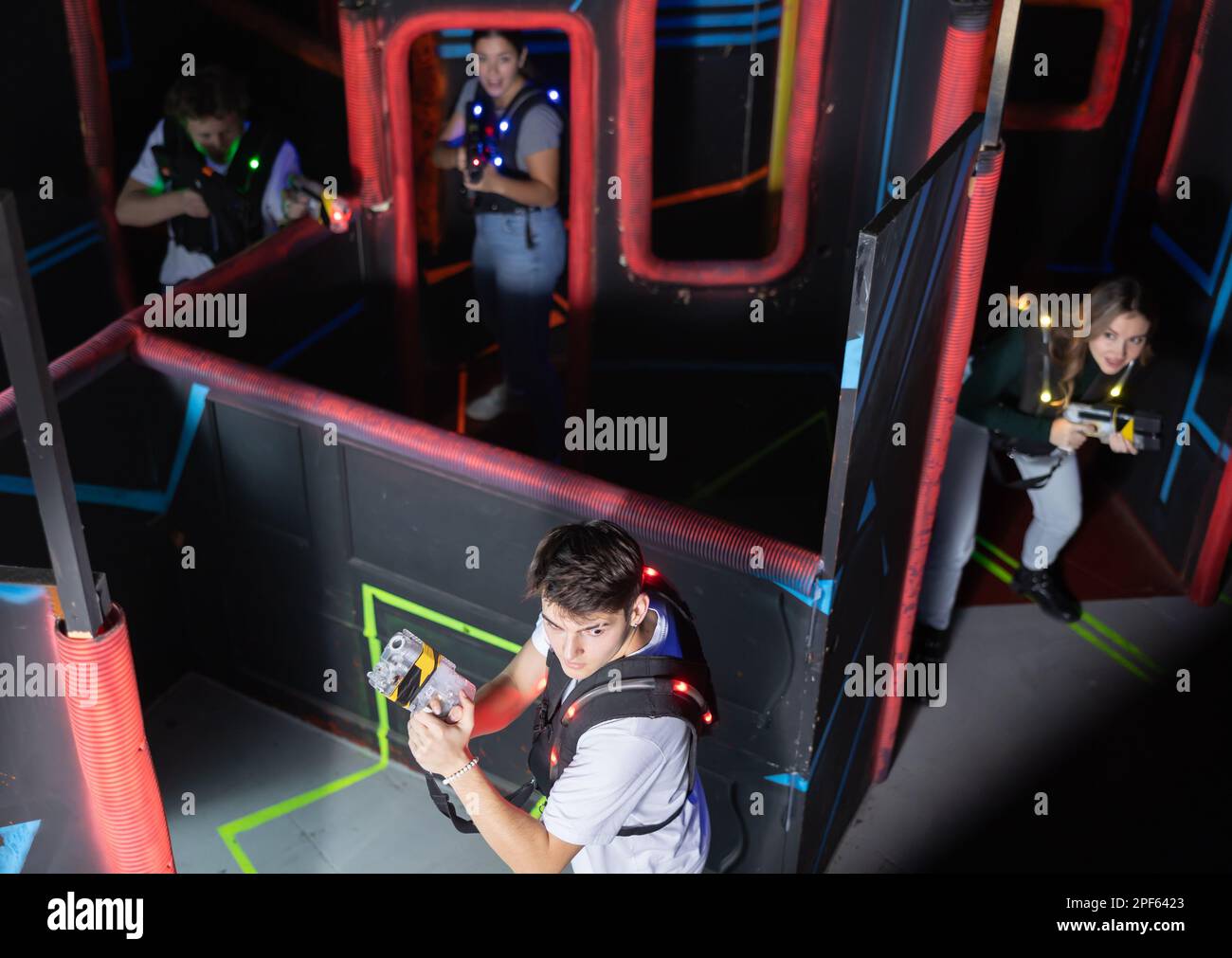 Laser tag players positive smiling guys and girls playing in teams in ...