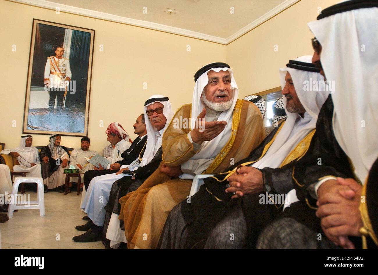 A portrait of the late King Faisal II hangs above family members and ...