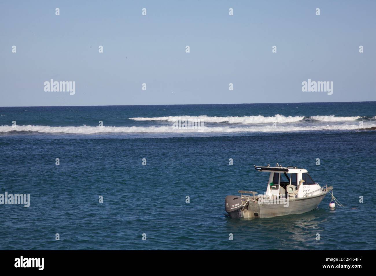 A sailboat floating peacefully on a tranquil blue ocean with gentle ...