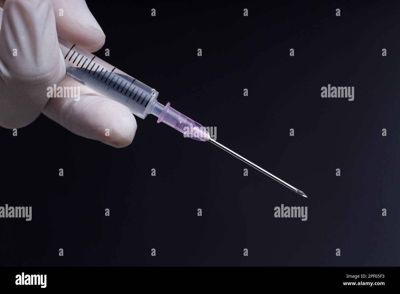 Gloved hand holding a syringe. Doctor or nurse wearing protective ...