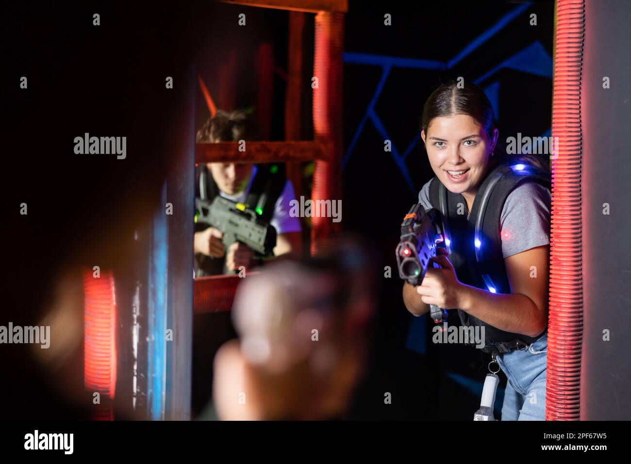 Positive girl holding laser pistol playing laser tag game with friends Stock Photo - Alamy