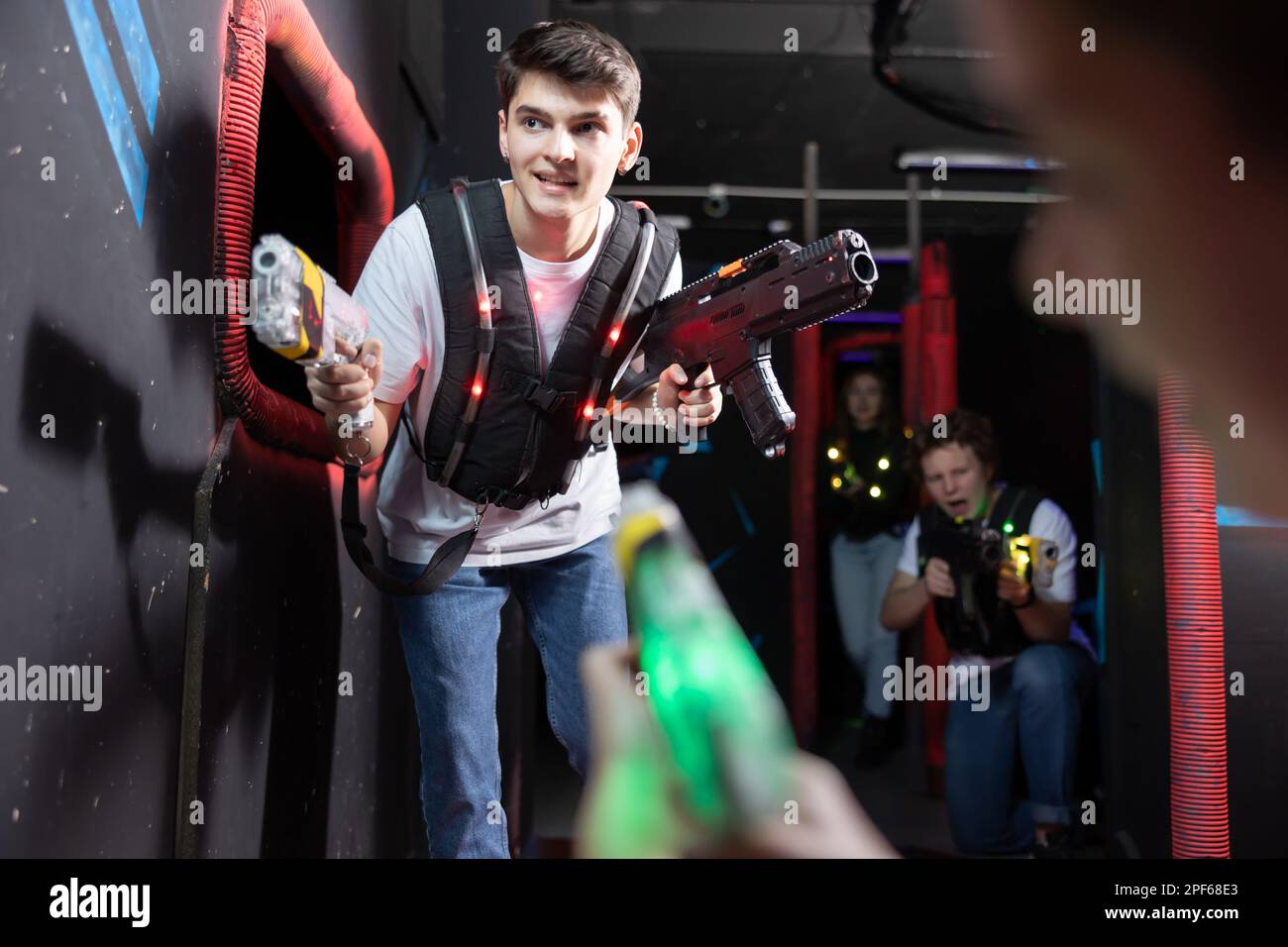 Emotional man with laser pistol playing laser tag with friends on dark ...