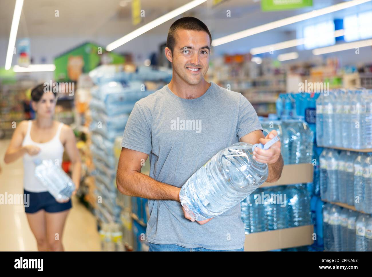 Portrait of adult man choosing water in bottle at supermarket Stock ...
