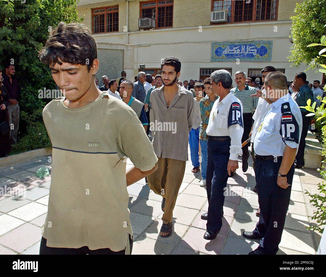 Iraqi felons are escorted back to jail after a hearing in a court in ...