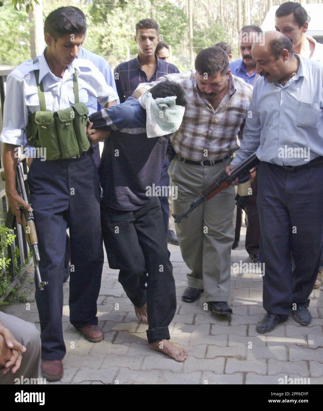 New Iraqi police drag a blindfolded robbery and murder suspect after he ...