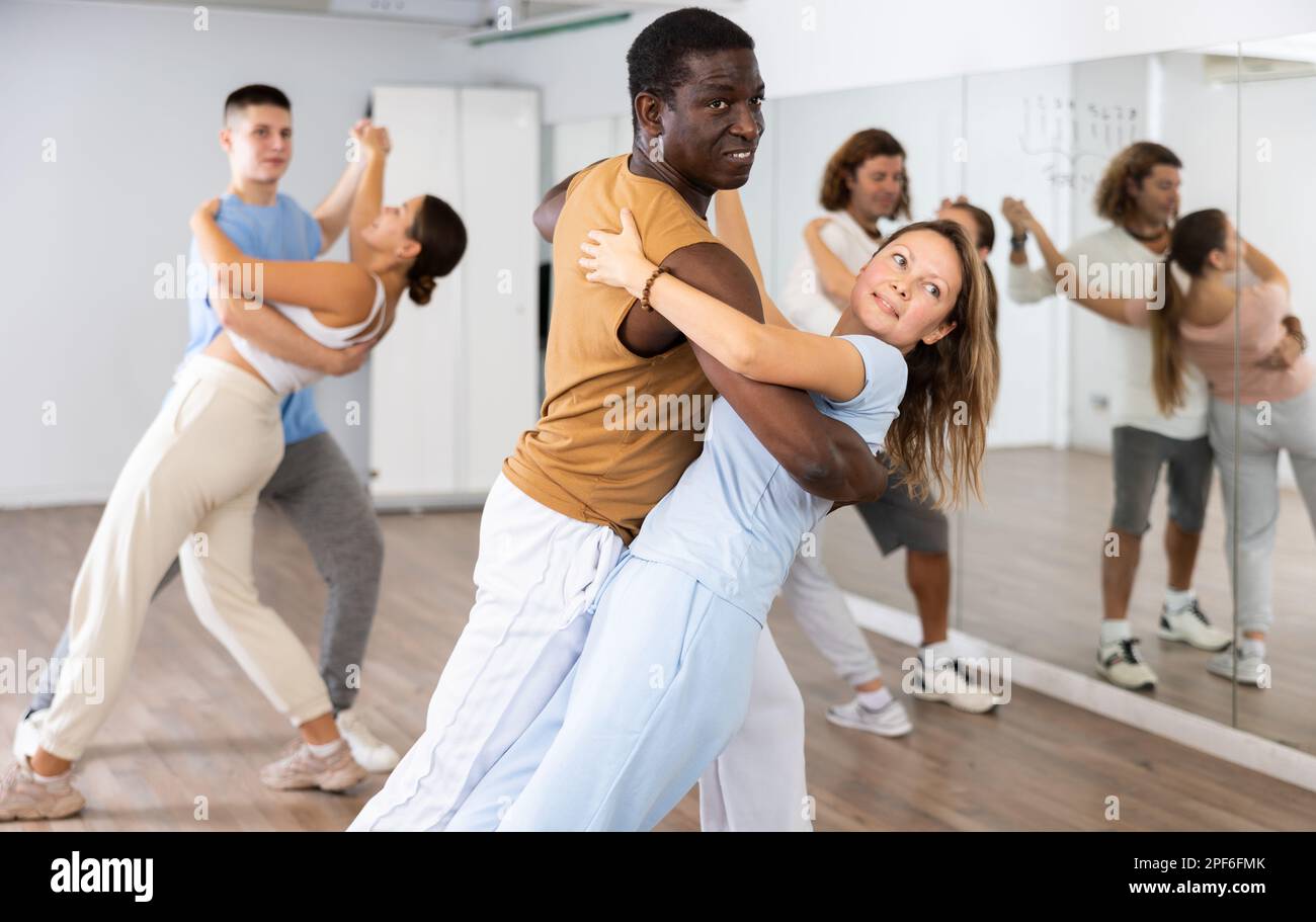 Portrait of positive adult couples dancing tango together in studio ...