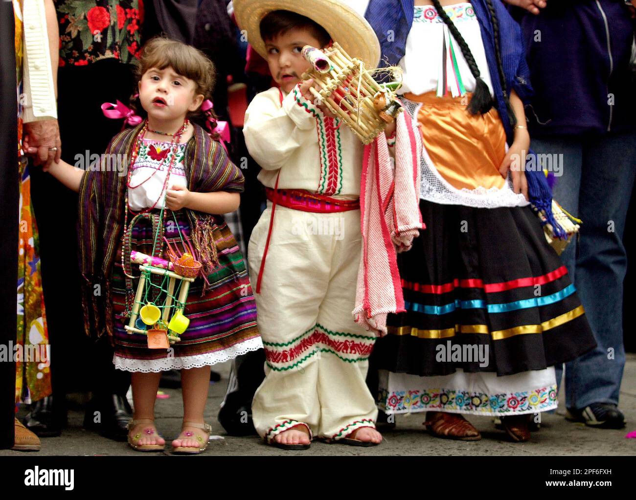 Children dressed in traditional Mexican attire wait for the procession ...