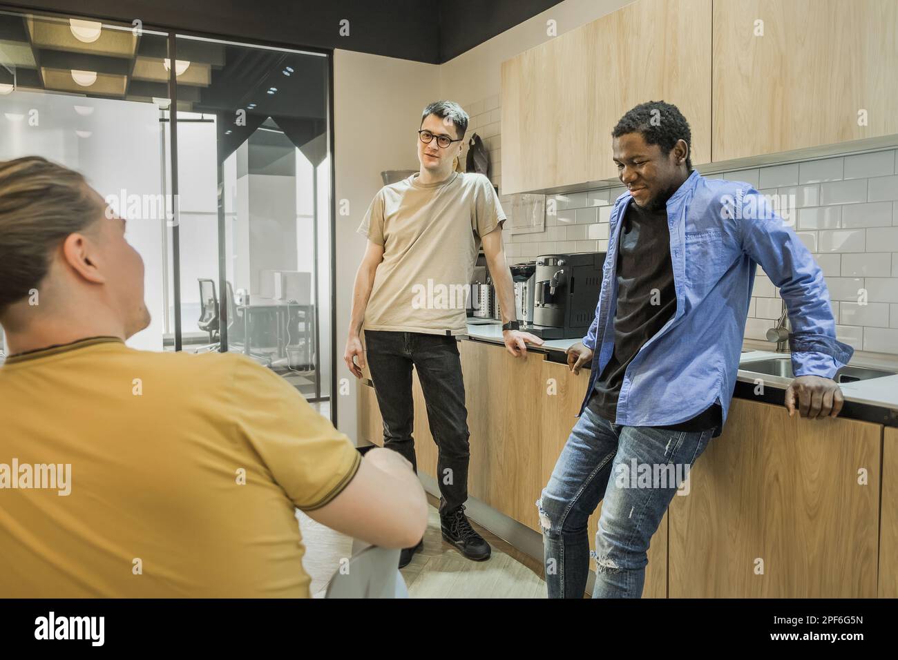 Group of cheerful young people talking and smiling during coffee break ...
