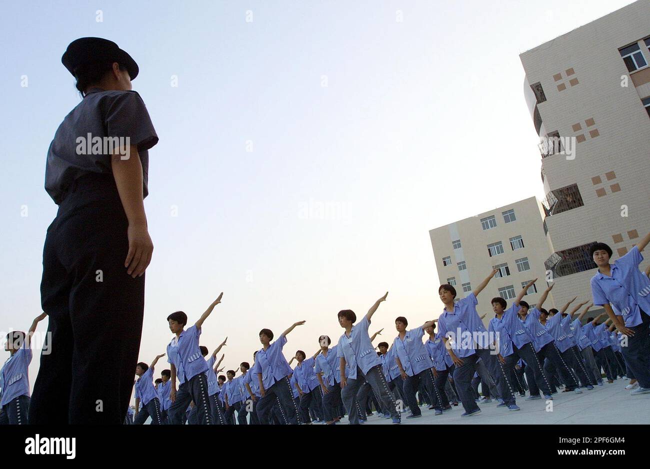 Chinese female prisoners perform exercises under the watch of a police ...