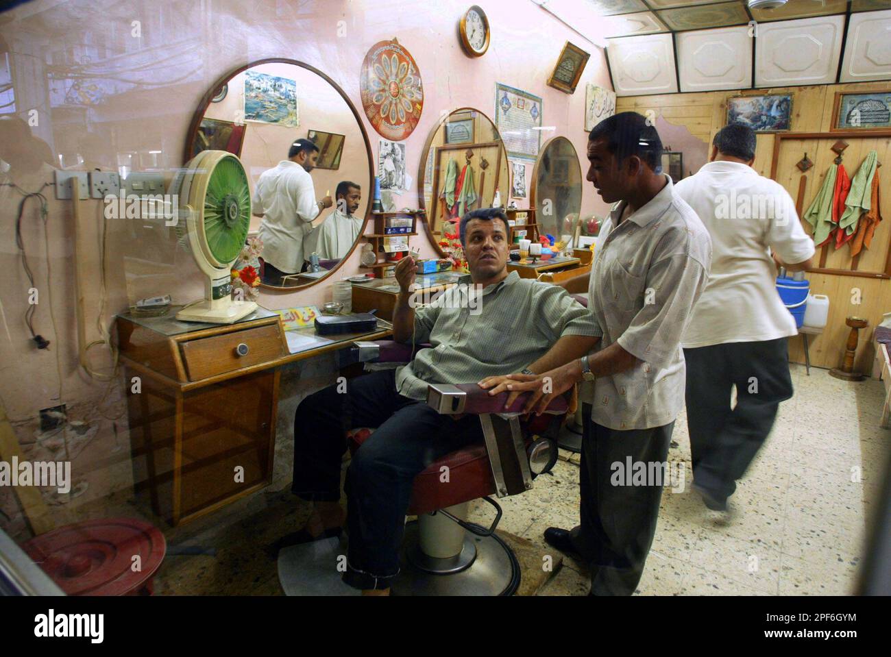 Men get groomed at a local barber in the town of Nasariyah, June 5 ...