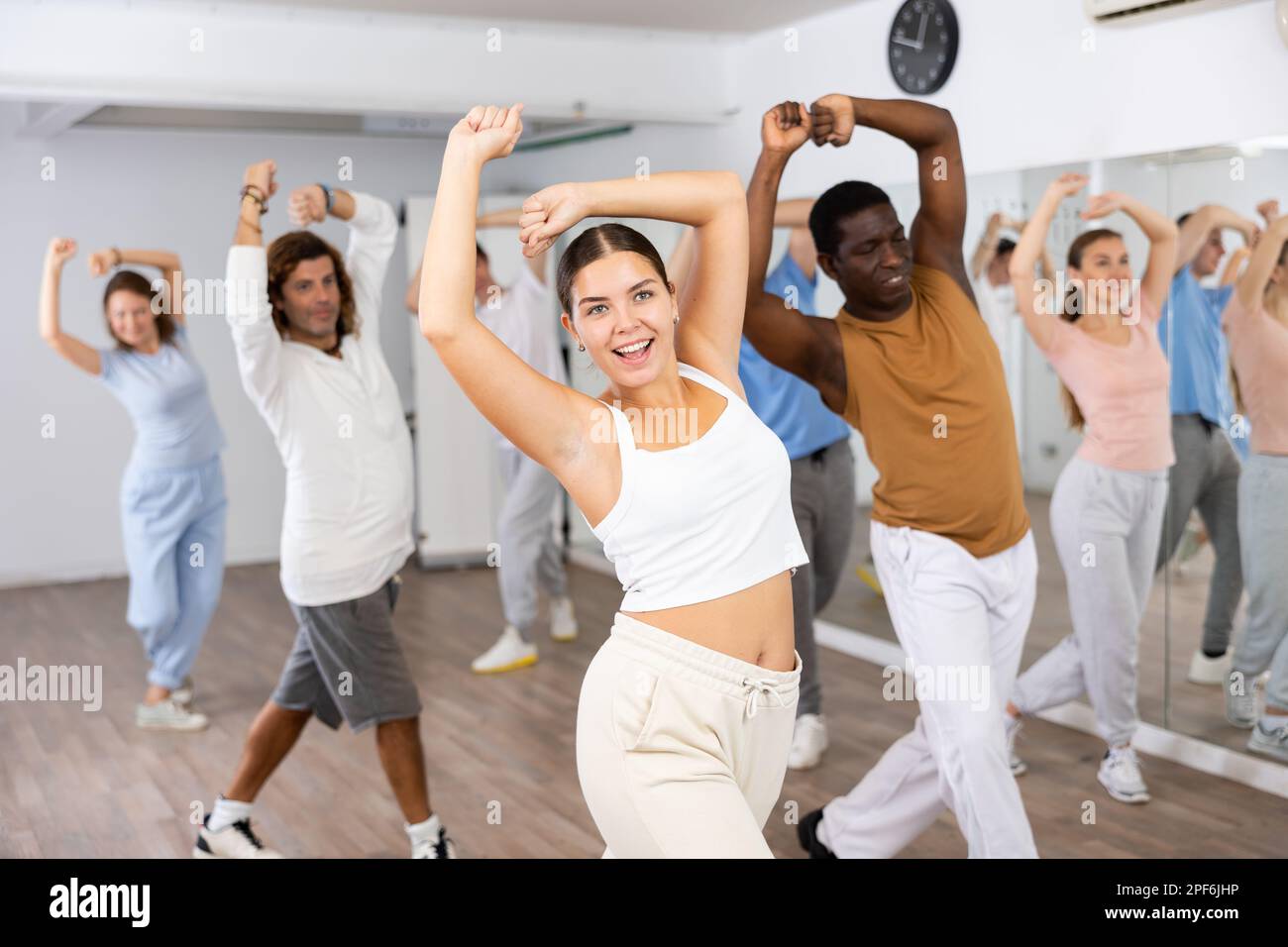 Group of young adult dancers raising both hands up during exercising in ...