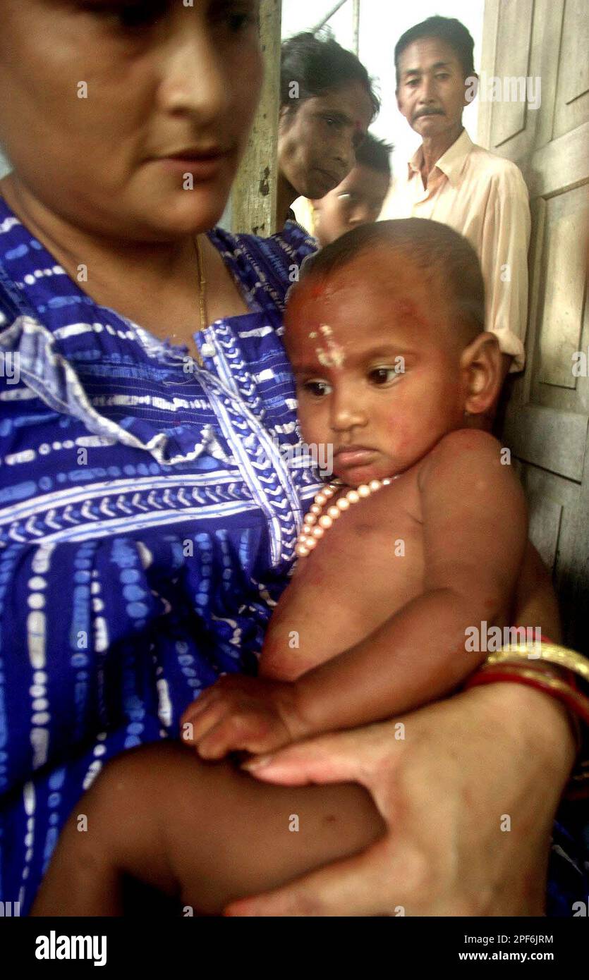One and half-year-old Taramai is carried by a woman after she was saved ...