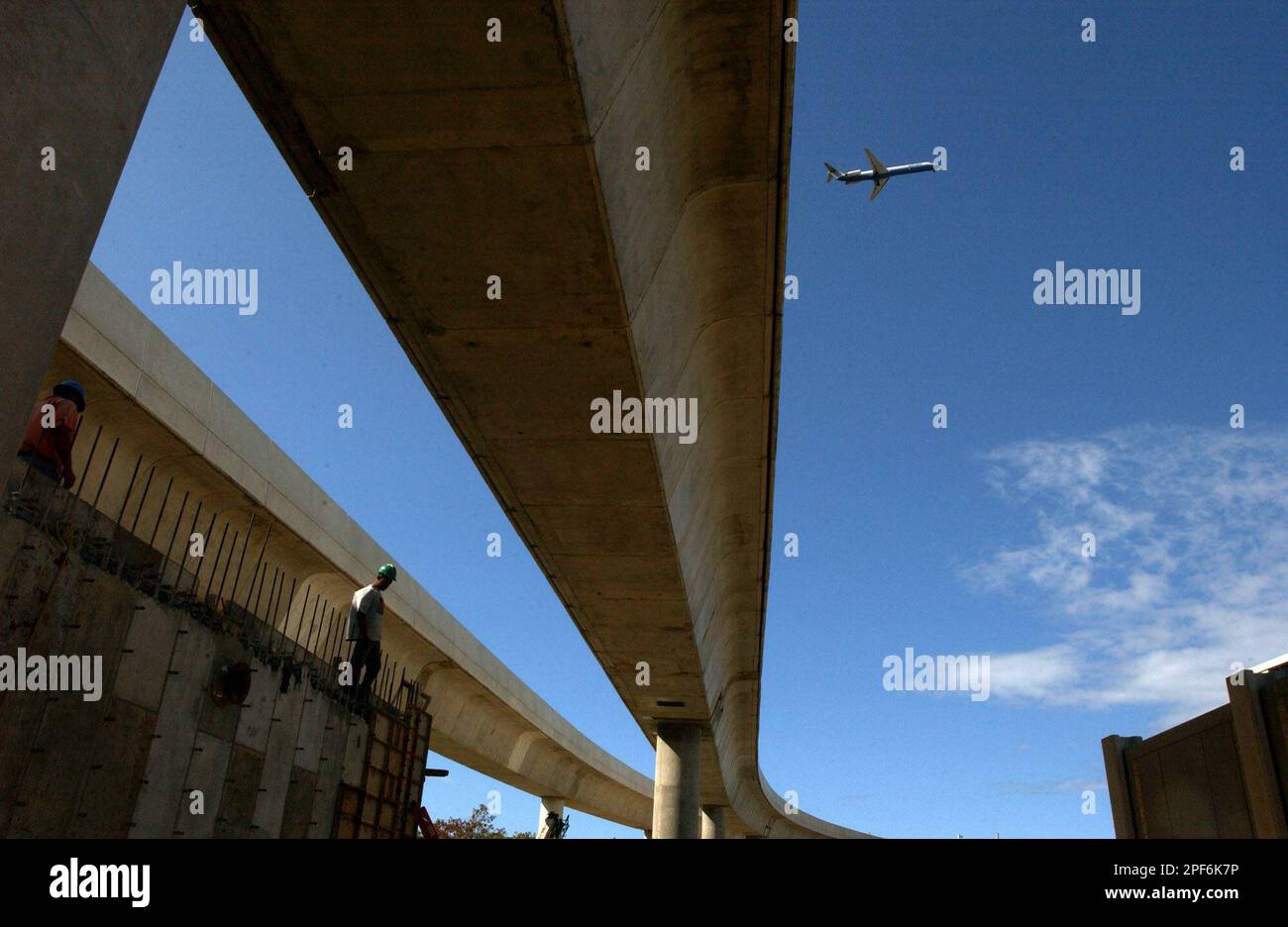 A construction worker pauses below a raised train track in San Juan ...