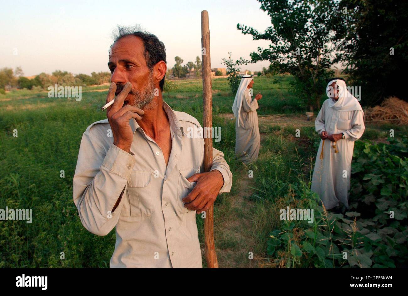 Abdul Karim, 53, left, smokes a cigarette after finishing watering a ...