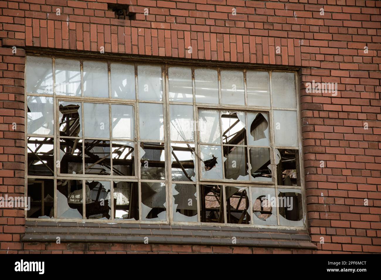 View through broken windows in a red brick wall to the open roof of a ...