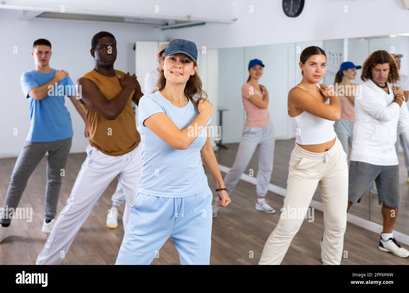 Women and men dancing synchronous group choreography in dance hall ...