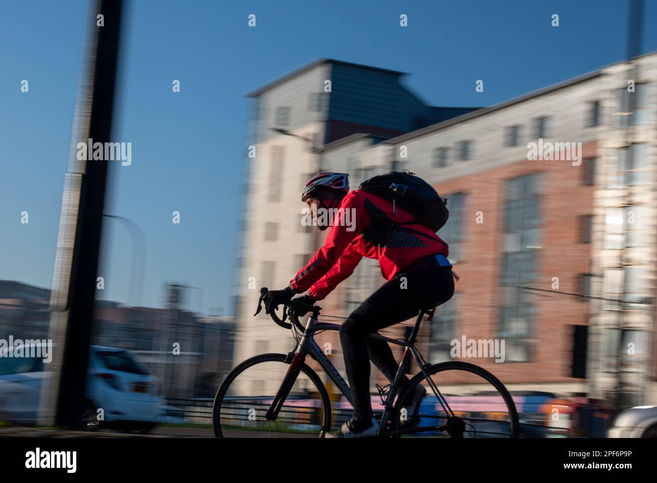 Cyclist wearing helmet and backpack riding fast in an urban environment ...