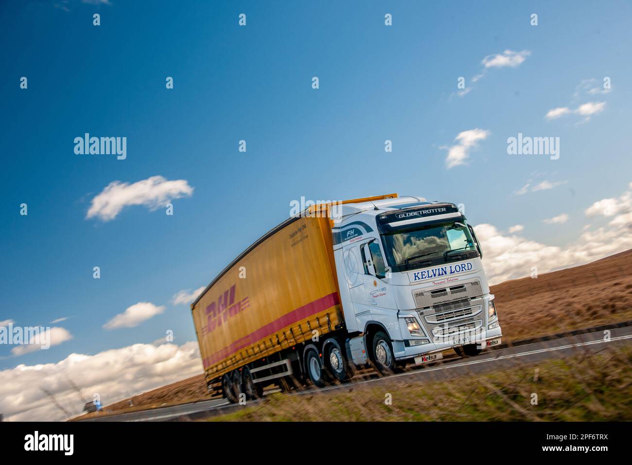 A Volvo truck pulling a DHL cutainsider trailer heads over the moors on ...
