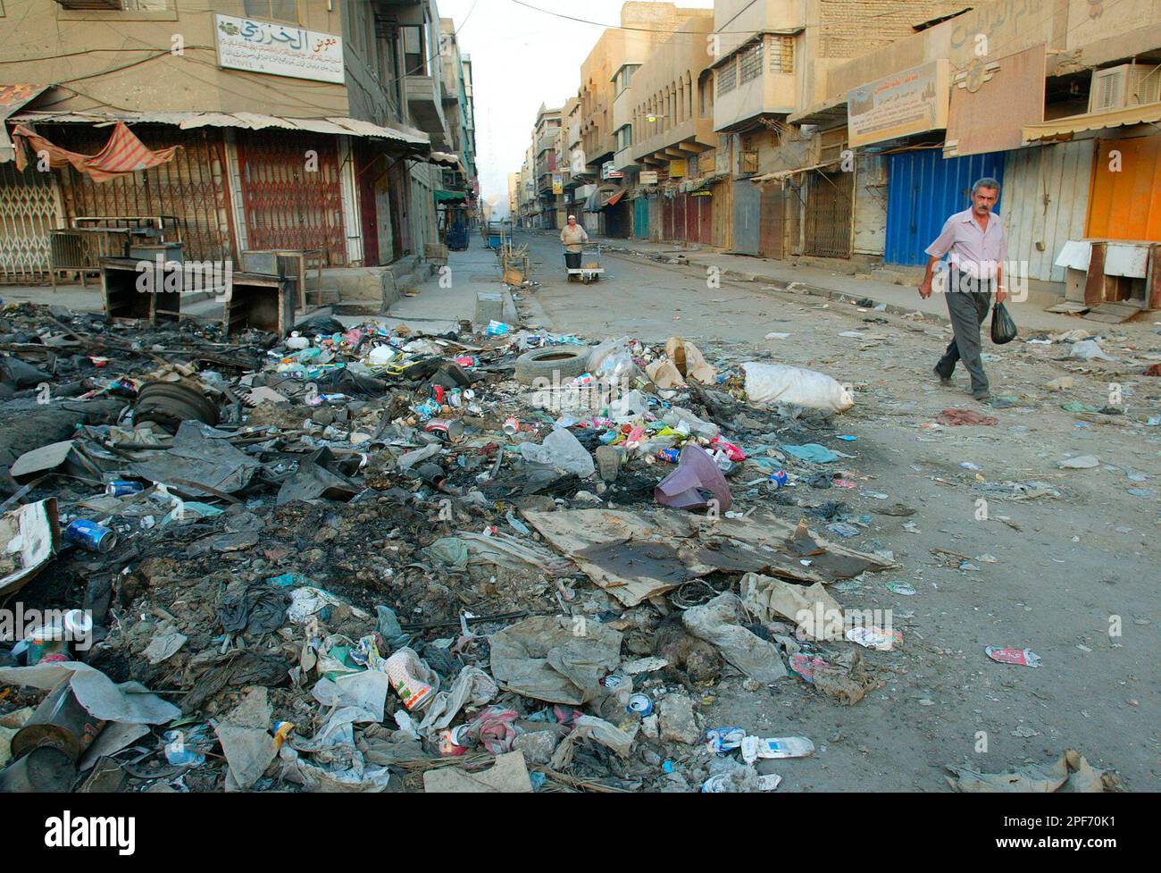 A local resident walks past uncleared garbage in Baghdad, Iraq, Sunday ...