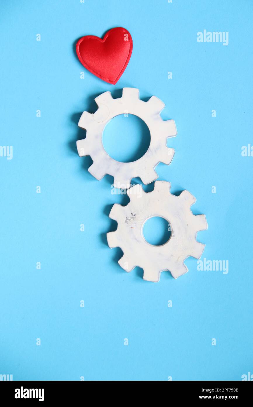 Gear wheels with heart symbol, blue background Stock Photo - Alamy
