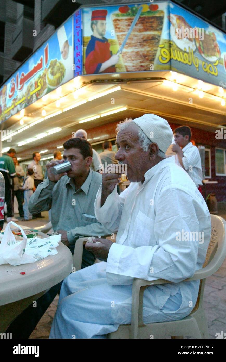 Iraqi men eat at a street side cafe in the center of Baghdad early ...