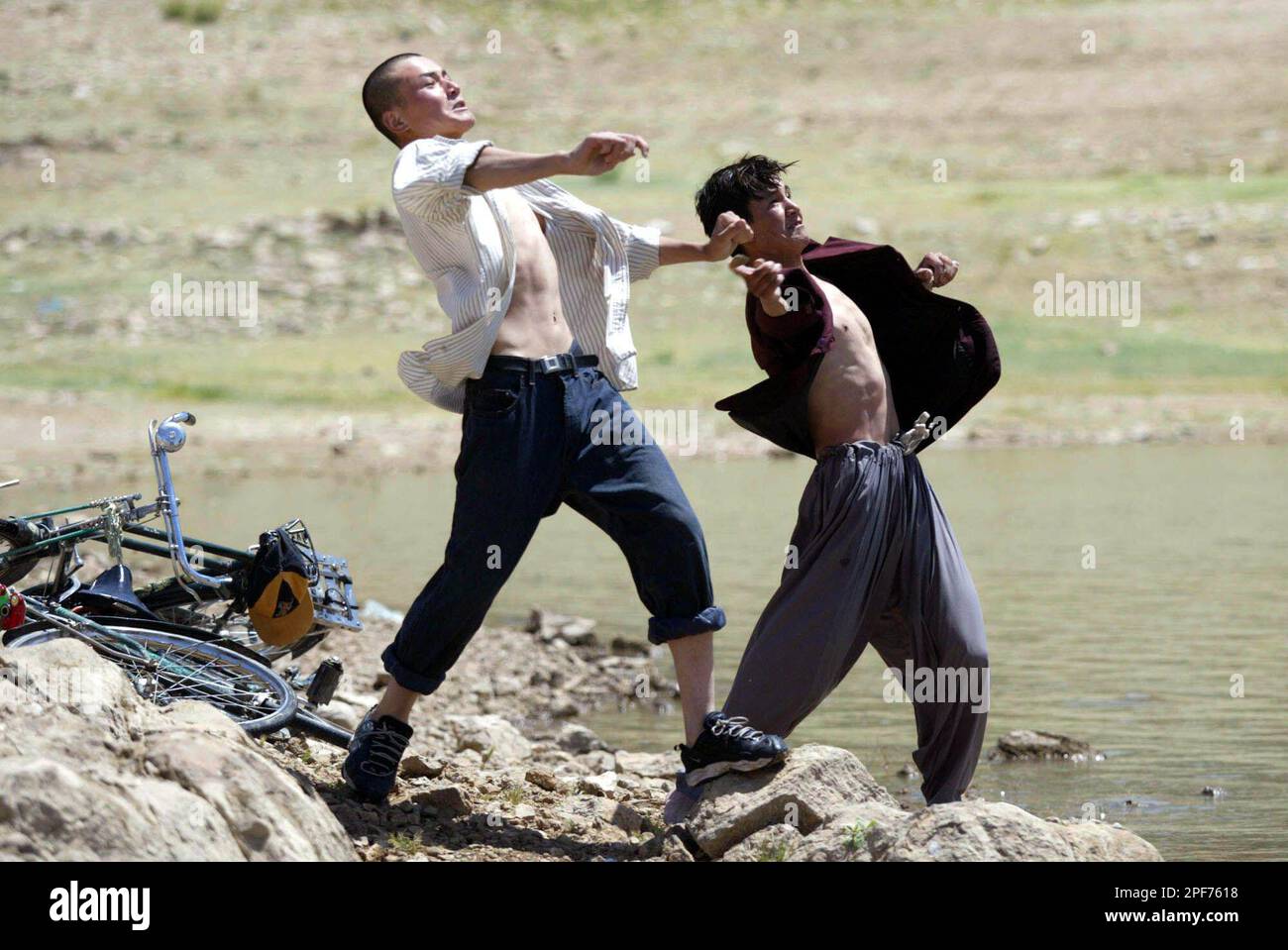 Two men compete throwing rocks to the lake at the outskirts of Kabul ...