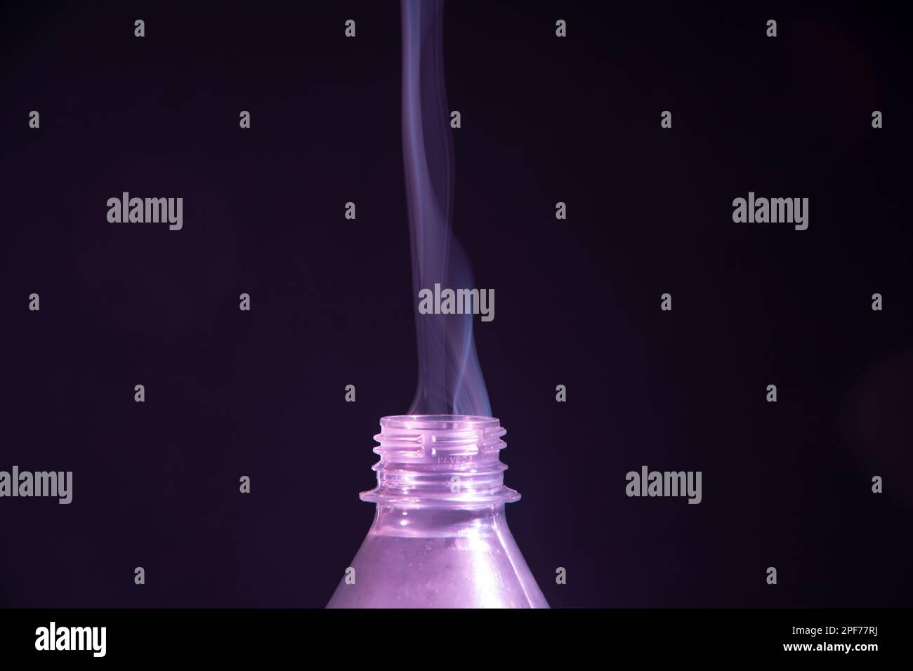 Smoke coming out of a plastic bottle against a black background. Design ...