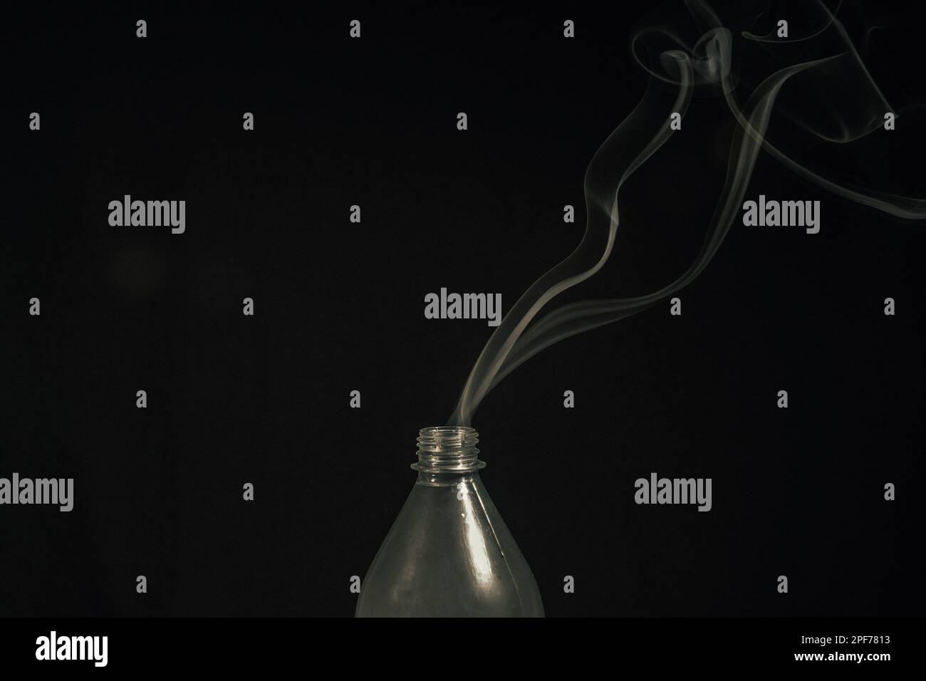 Smoke coming out of a plastic bottle against a black background. Design ...