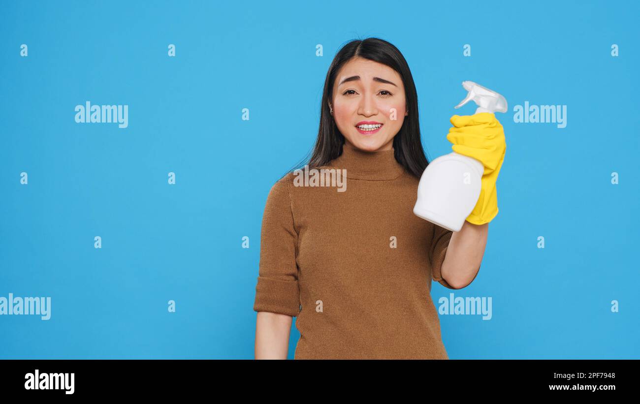 Asian housekepper pointing and showing hygiene products or isolated ...