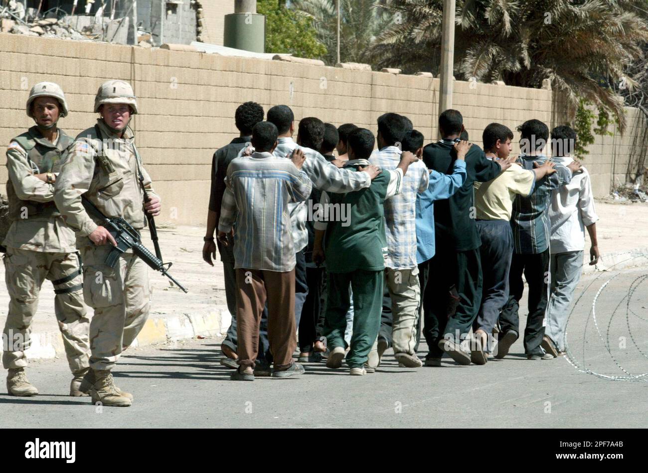 U.S. soldiers keep guard of detained Iraqi looters outside of a Saddam ...