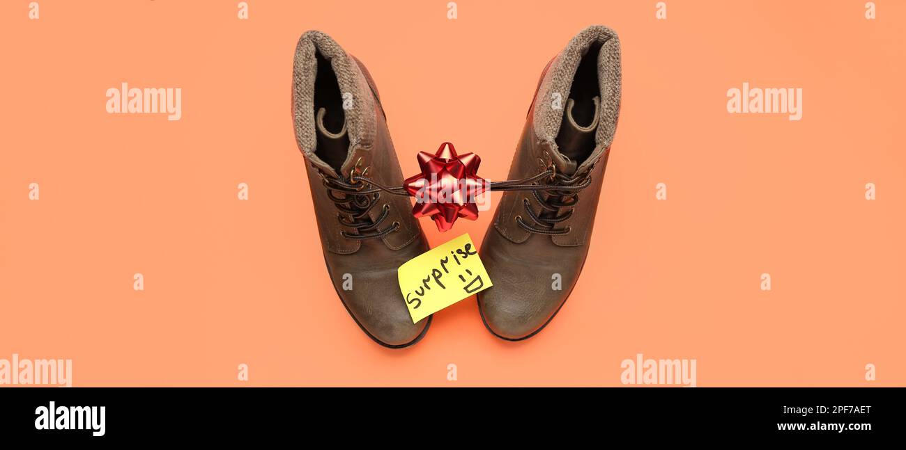 Paper with word SURPRISE, boots and ribbon bow on orange background ...