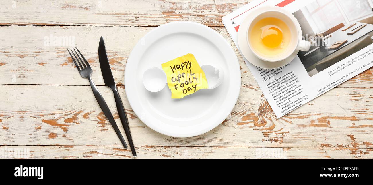 Paper with text HAPPY APRIL FOOLS DAY, egg, cup, cutlery and newspaper ...