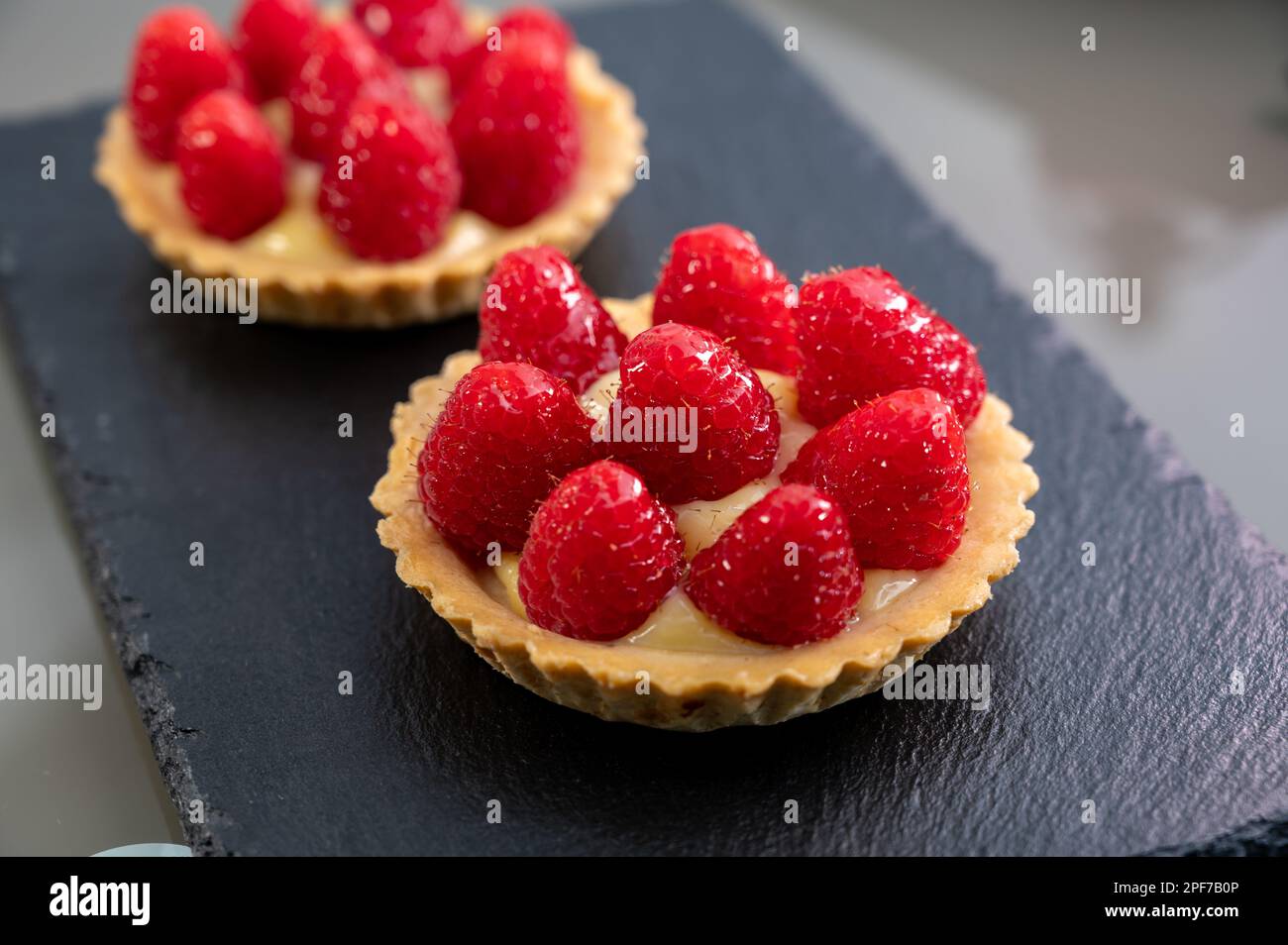 Artisanal baked small tart with cream and fresh ripe red raspberry ...
