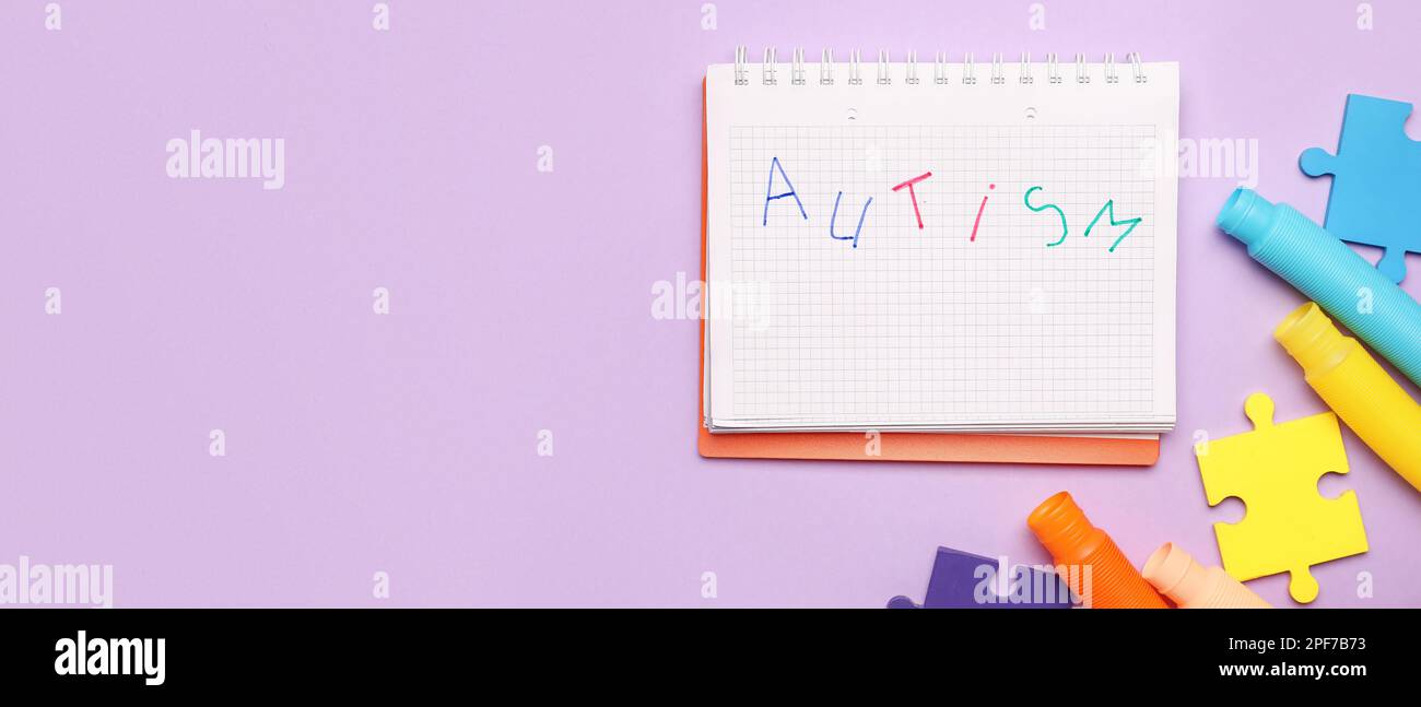 Notebook with word AUTISM, puzzle pieces and pop tubes on lilac ...