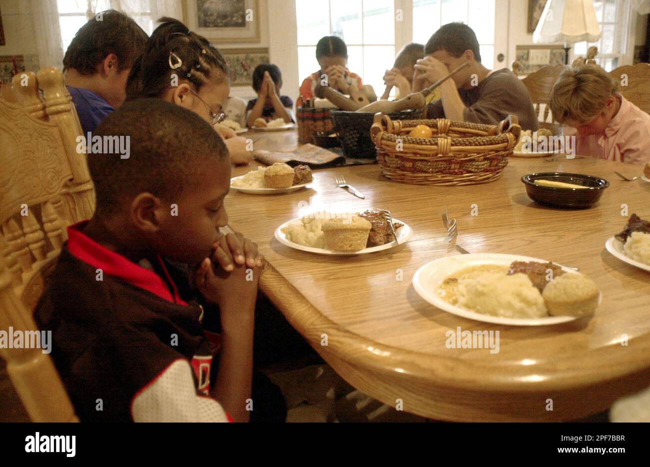 Marcus Schmitz, 8, front left, prays with his adopted siblings before ...