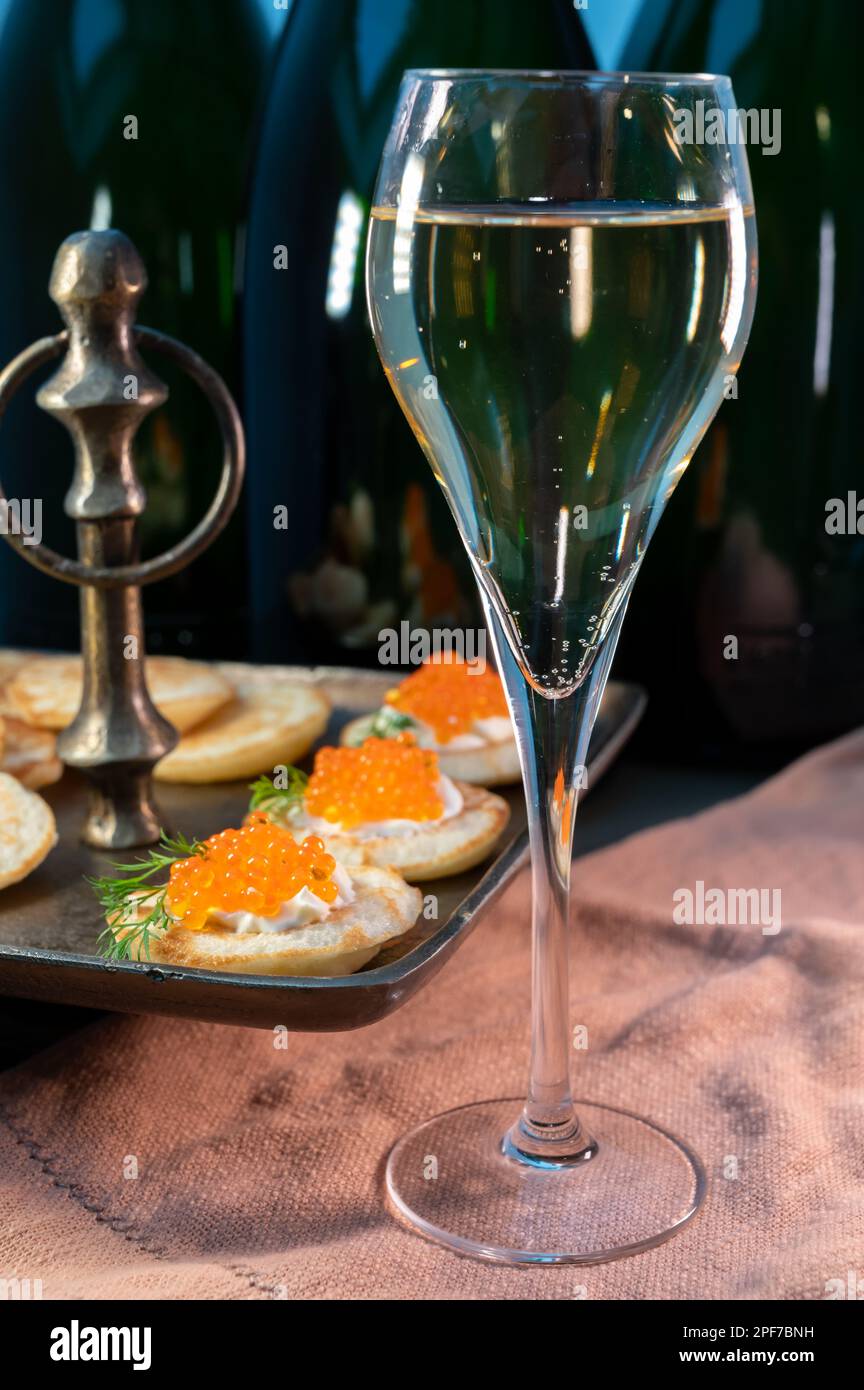 Tasting of brut Champagne sparkling wine with red caviar in cellars of ...