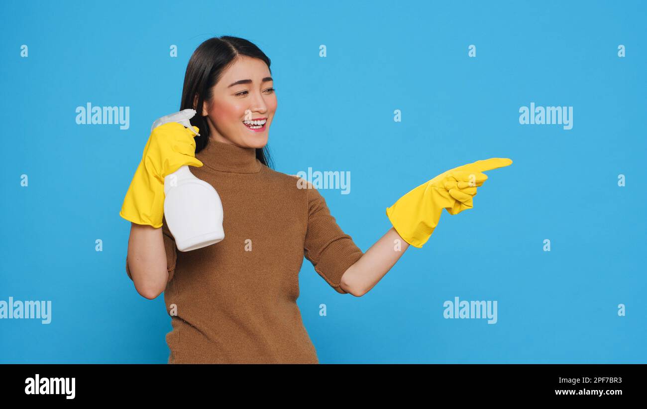 Cleaning woman pointing and showing cleaning product or isolated text ...