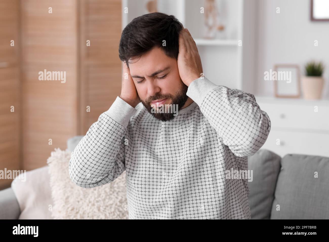 Young man suffering from loud noise at home Stock Photo - Alamy