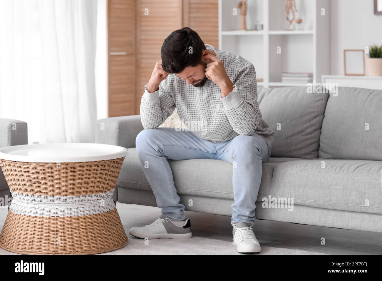Young man suffering from loud noise at home Stock Photo - Alamy