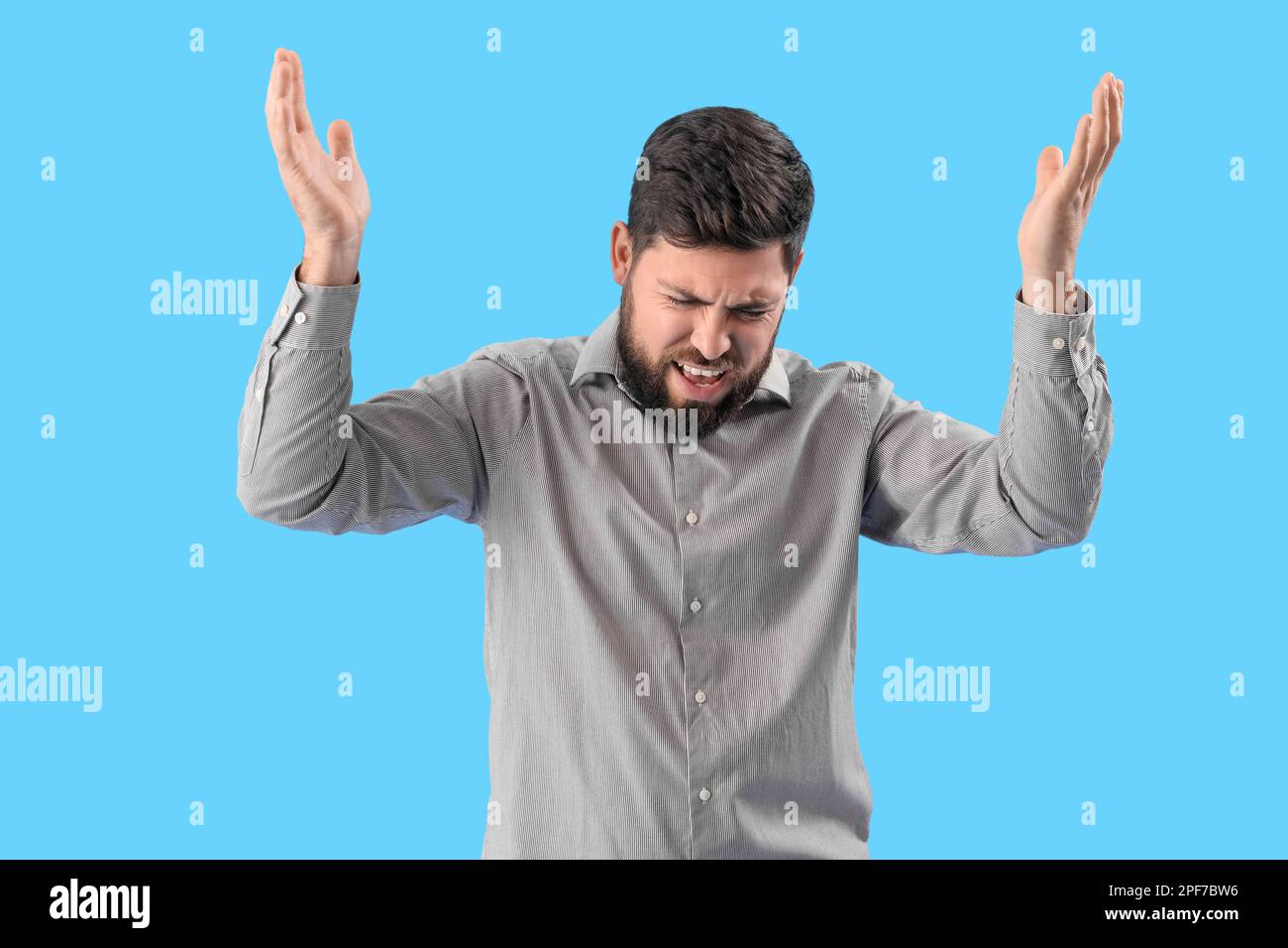 Stressed young man suffering from loud noise on blue background Stock ...