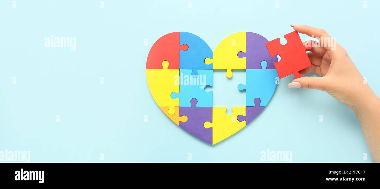 Hand and heart made of puzzle pieces on light blue background. Concept ...