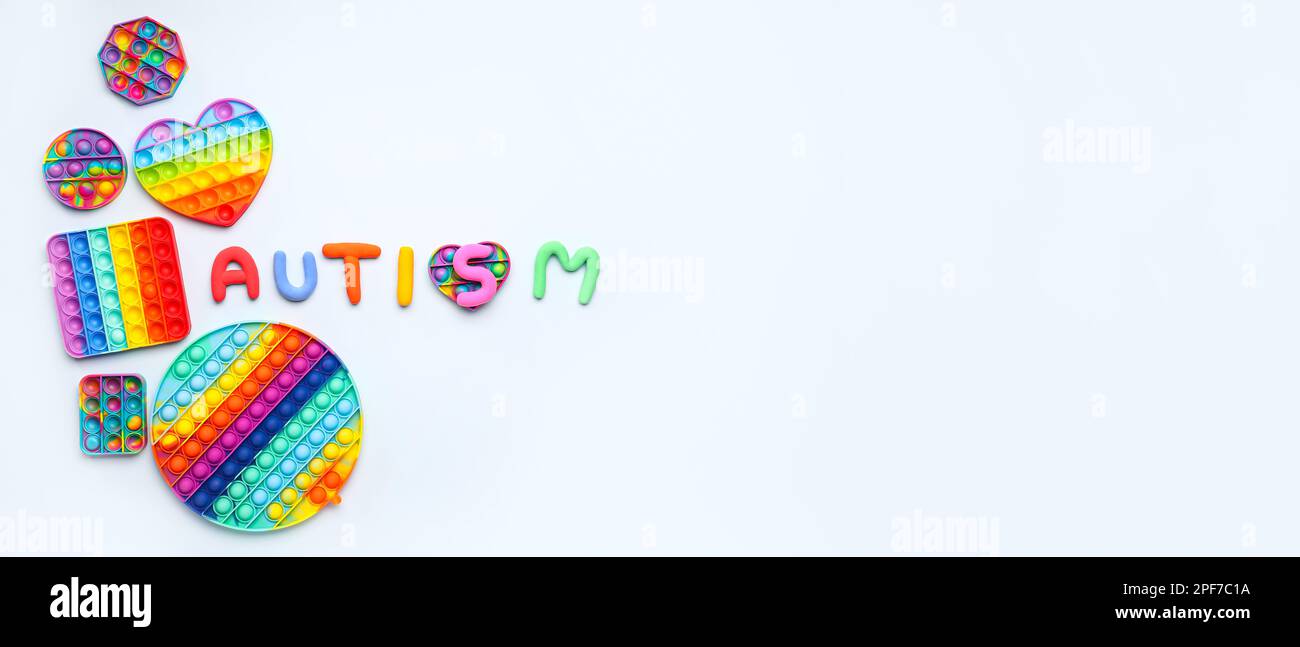 Word AUTISM and pop it fidget toys on white background with space for ...