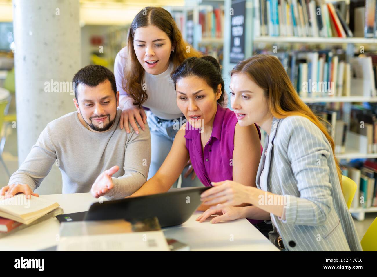 Group of friendly students working on joint research in library Stock ...